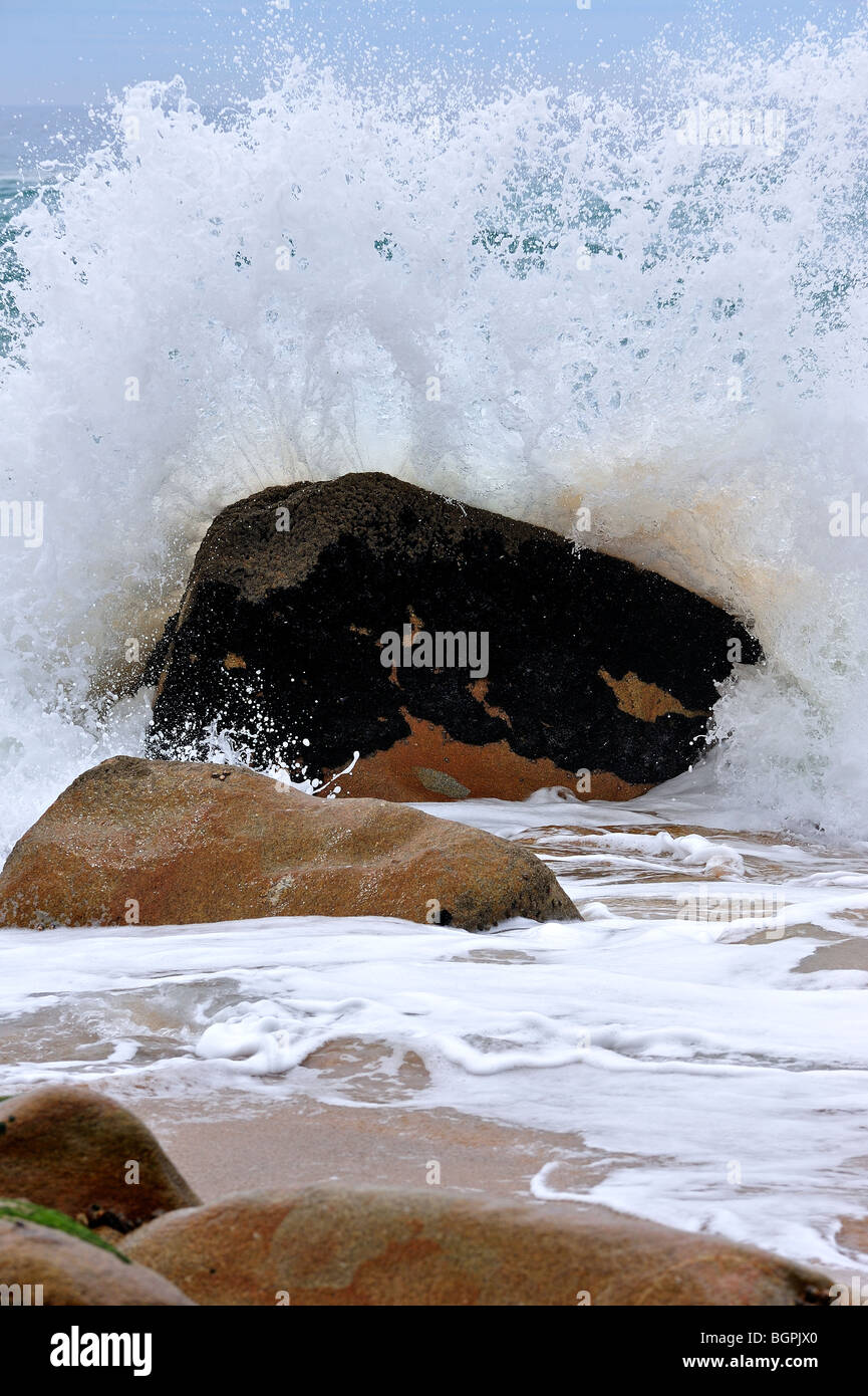 Wave crashing into boulder in the surf at the Côte Sauvage / Wild Coast ...