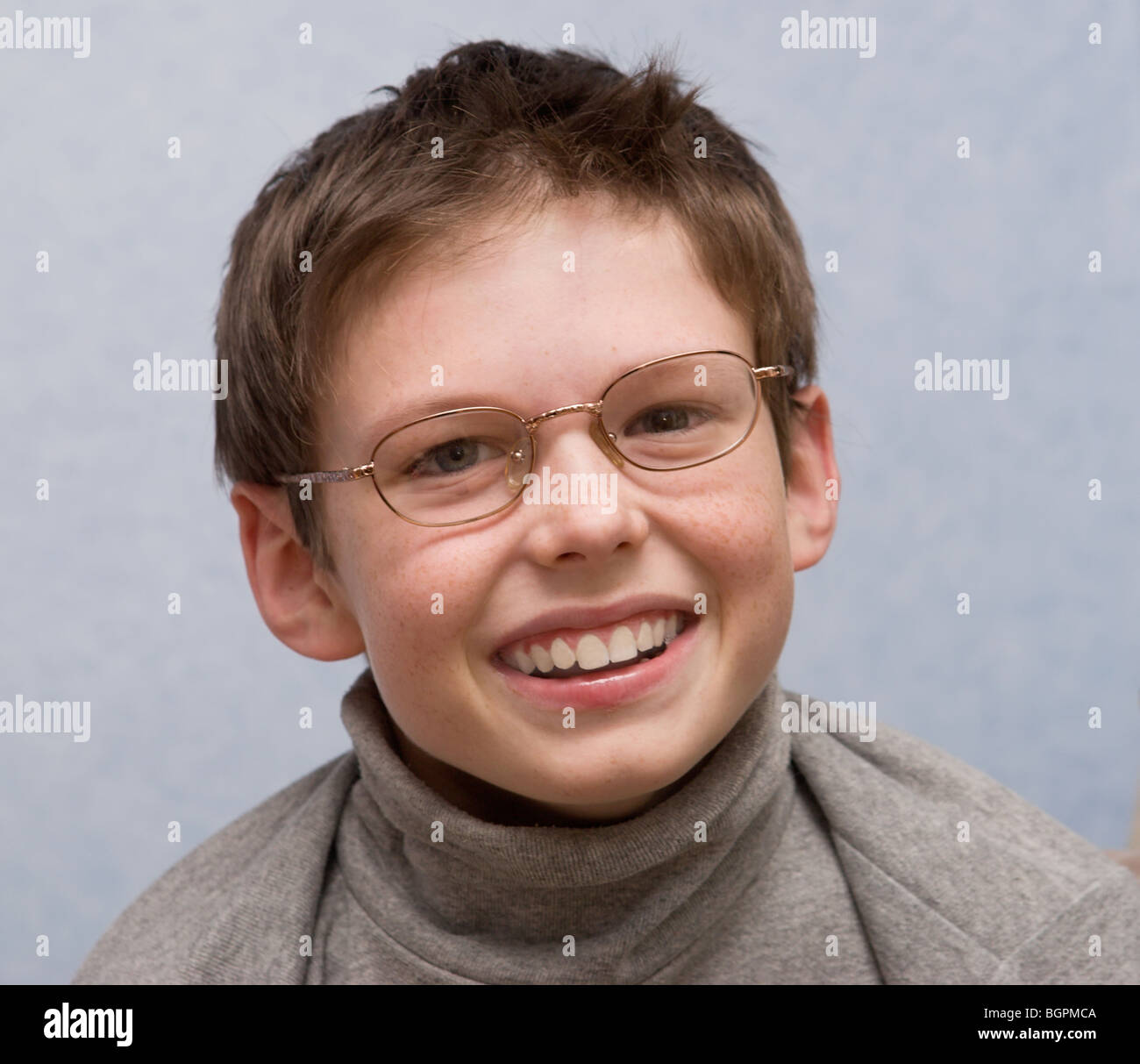 portrait of smiling teenager boy in glasses on light blue background ...