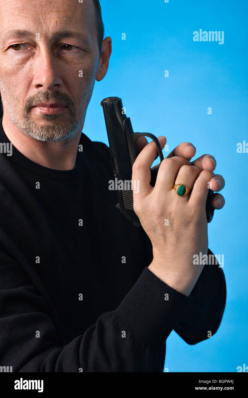 man with gun in hands. close-up portrait on blue background Stock Photo ...
