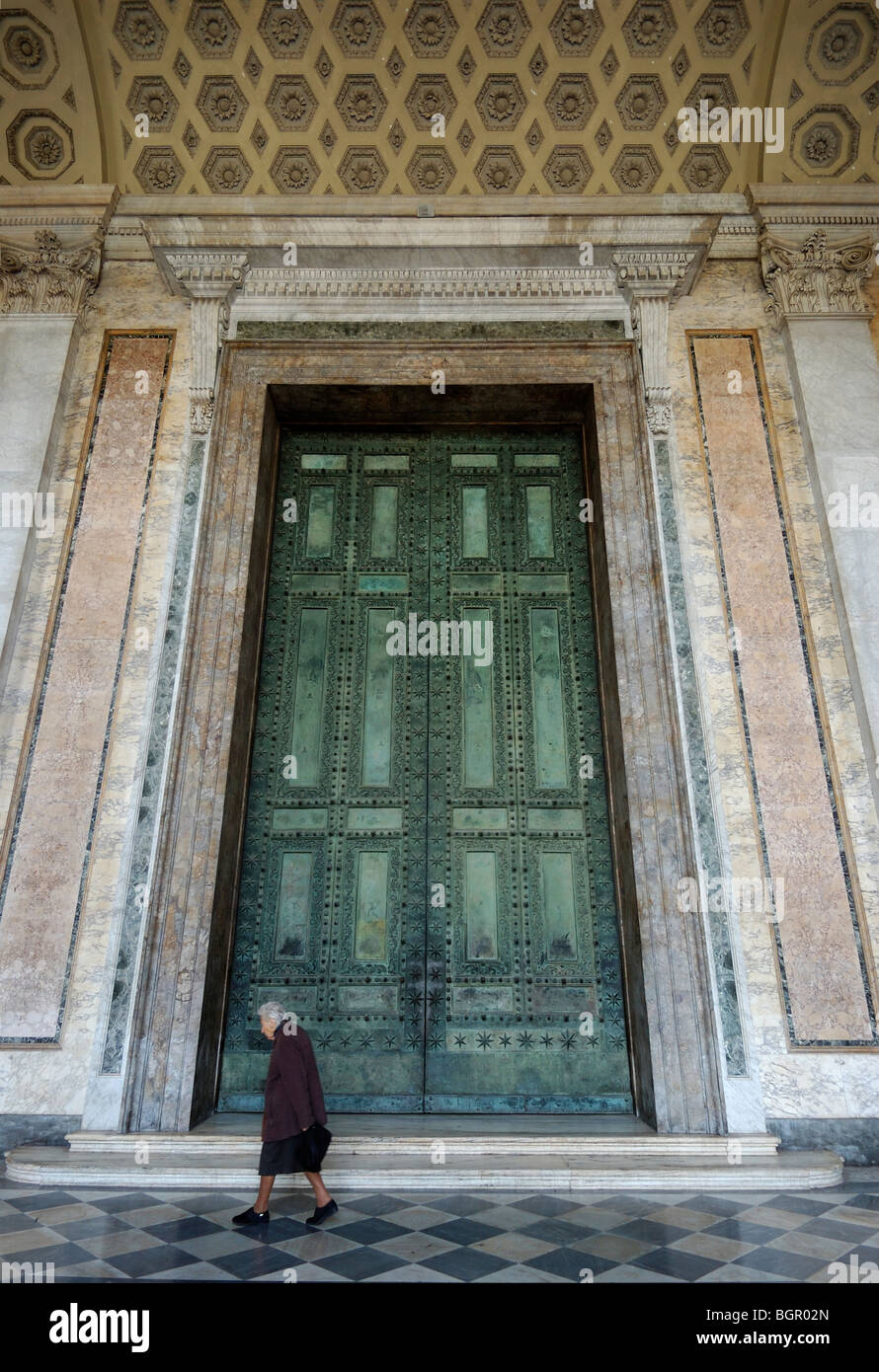 Woman walking past giant door to the Basilica of St John Lateran, Rome ...