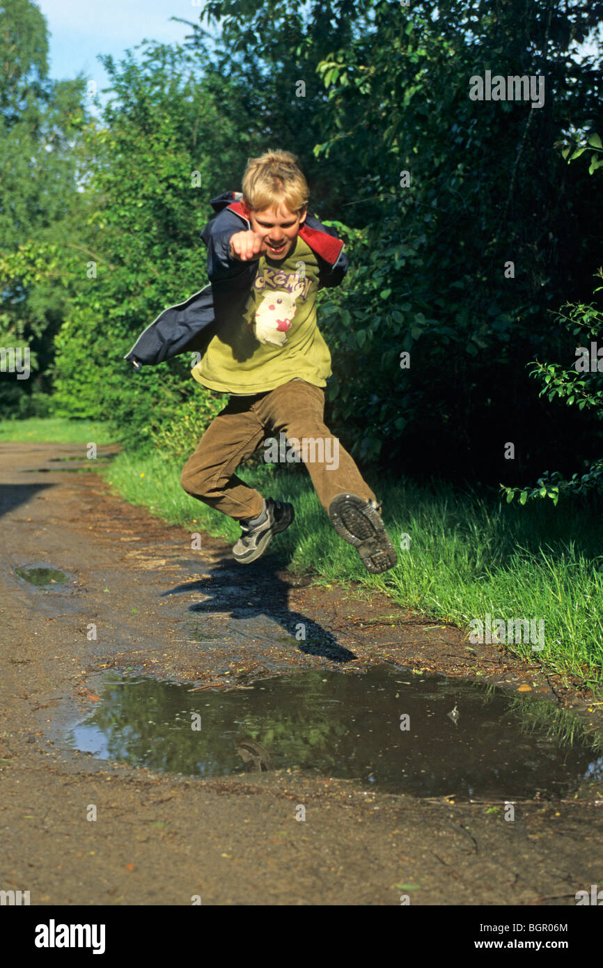 young boy jumping across a puddle Stock Photo - Alamy