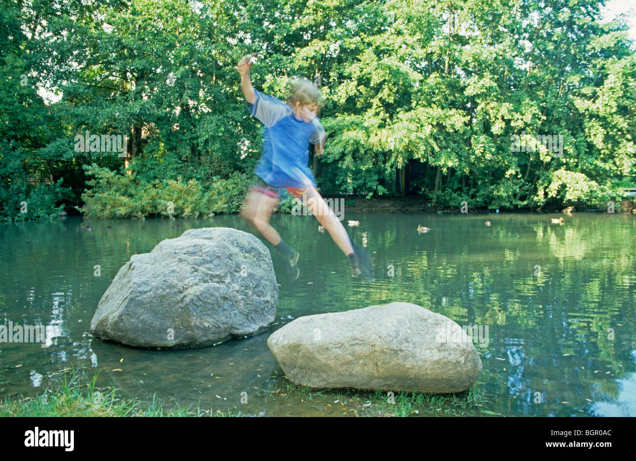 young boy jumping from one stone to another Stock Photo - Alamy