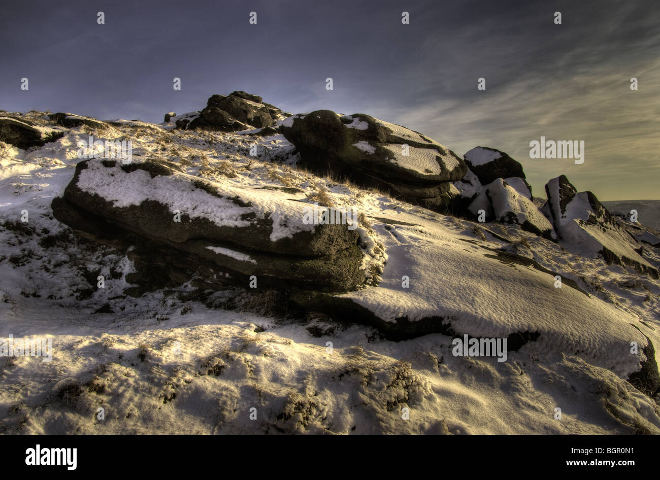 Weathered gritstone rocks and snow, lit by low afternoon sun ...