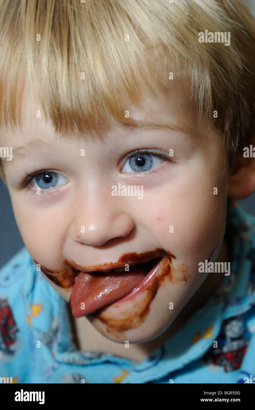 young child blond boy with chocolate smeared all over face Stock Photo ...