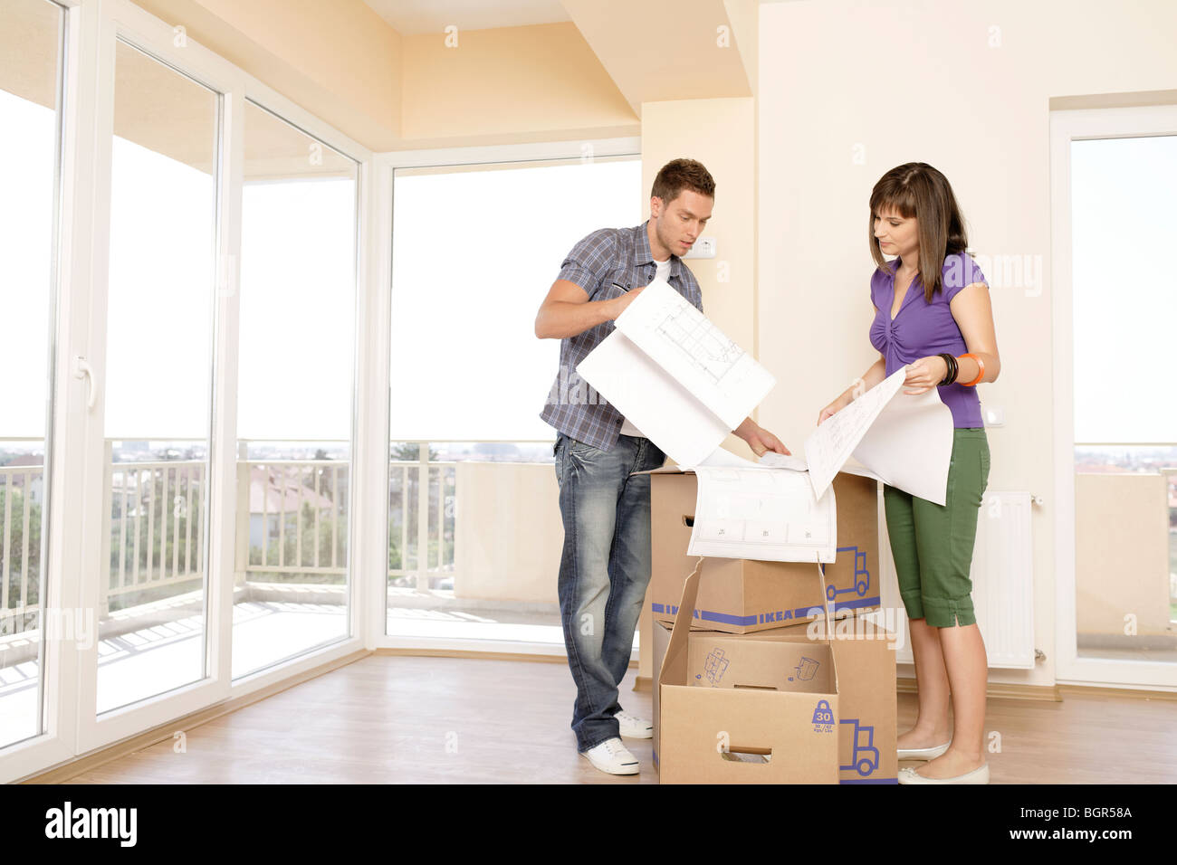 man and woman in an empty house with boxes near making plans on how to ...