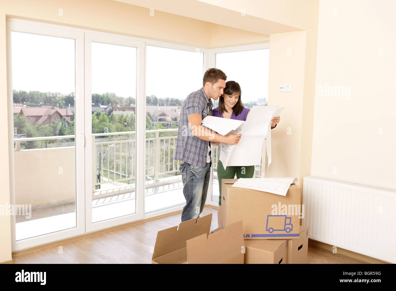 man and woman in an empty house with boxes near making plans on how to ...