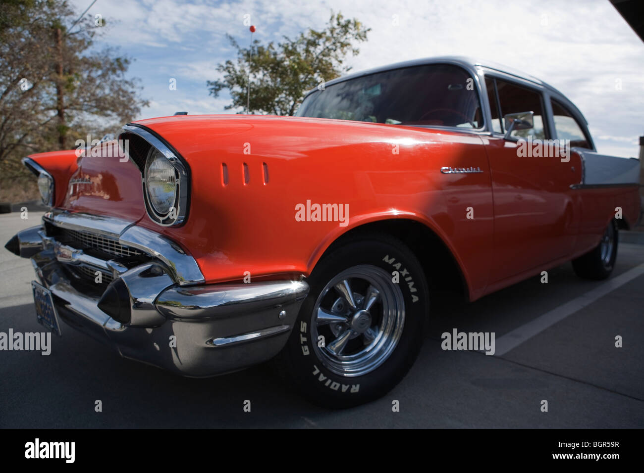 A 1957 Chevrolet sedan painted a bright redish orange and white in ...
