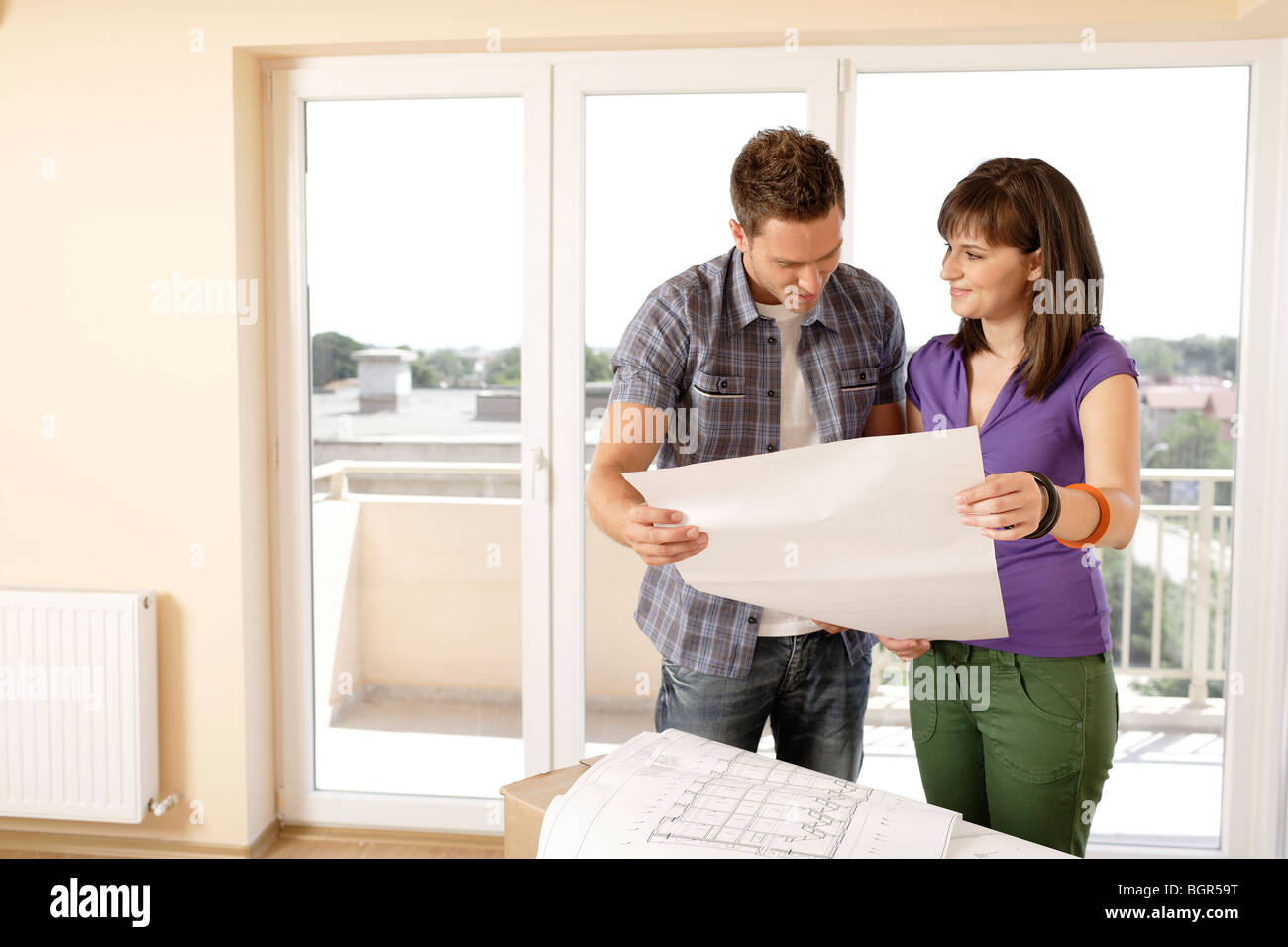 man and woman in an empty house with boxes near making plans on how to ...