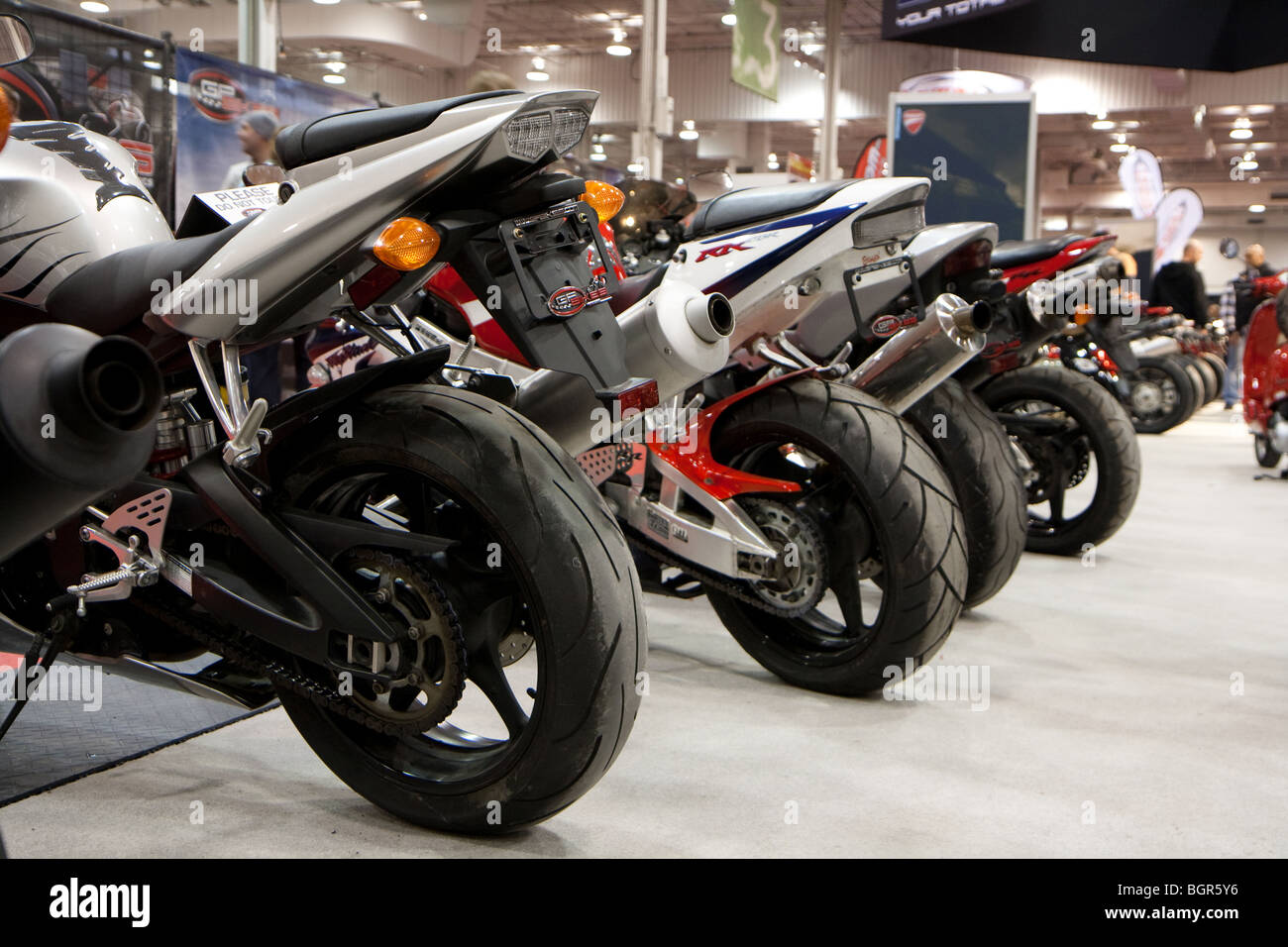 Rear view of motorbikes lined up on the floor at a motorcycle show ...