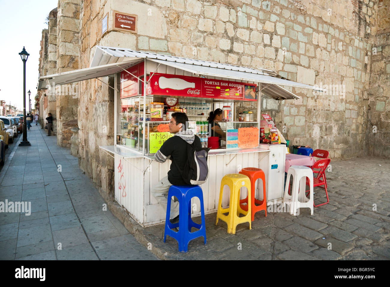 street corner sidewalk food stall with seating for customers tucked ...