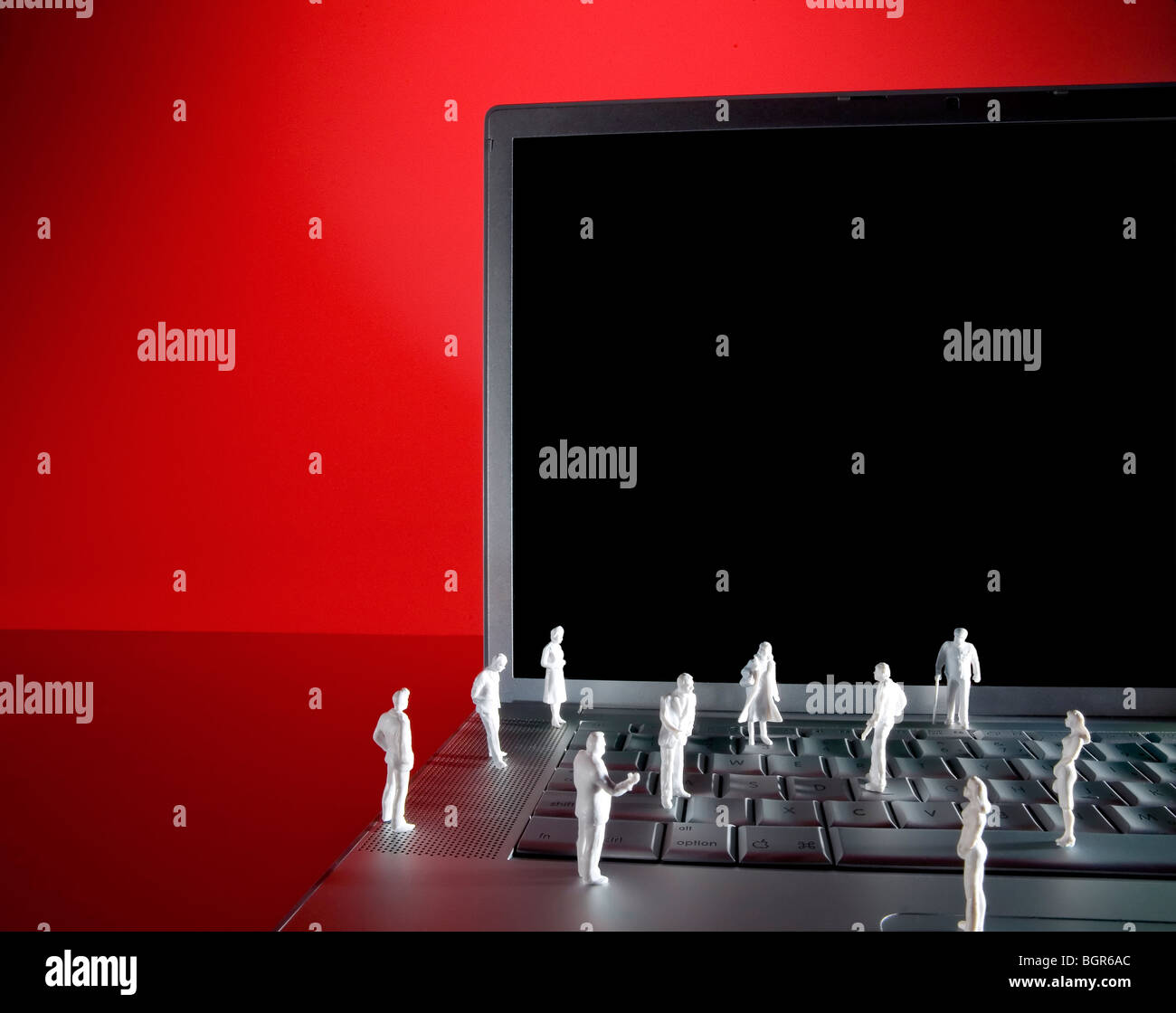 Miniature figures of people standing on keyboard of silver laptop ...