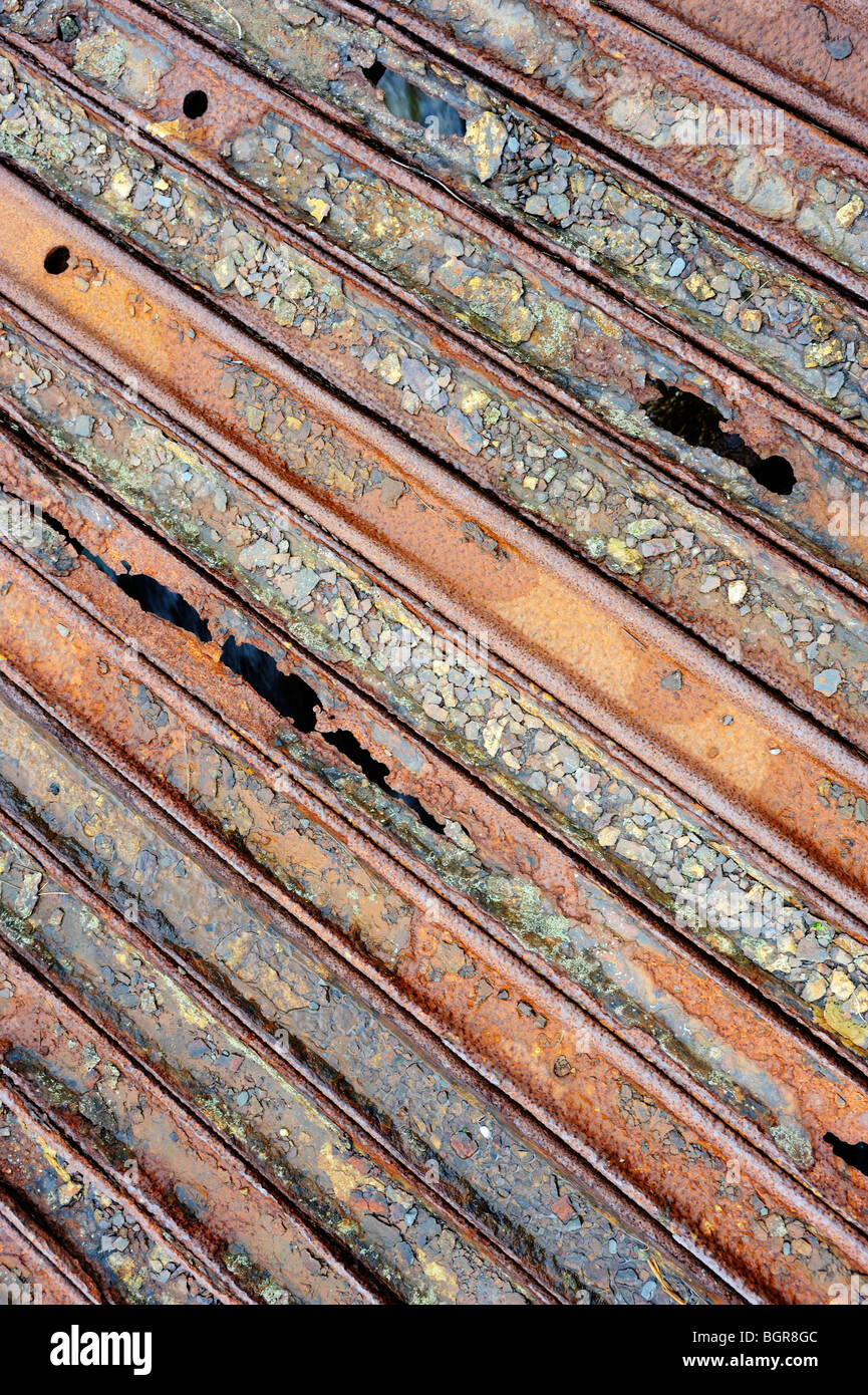 Rusting sections of railway track laid together to form a bridge across ...