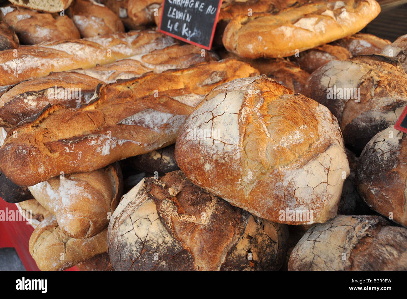 A creatively stacked pile of crusty French baguettes and boule bread ...