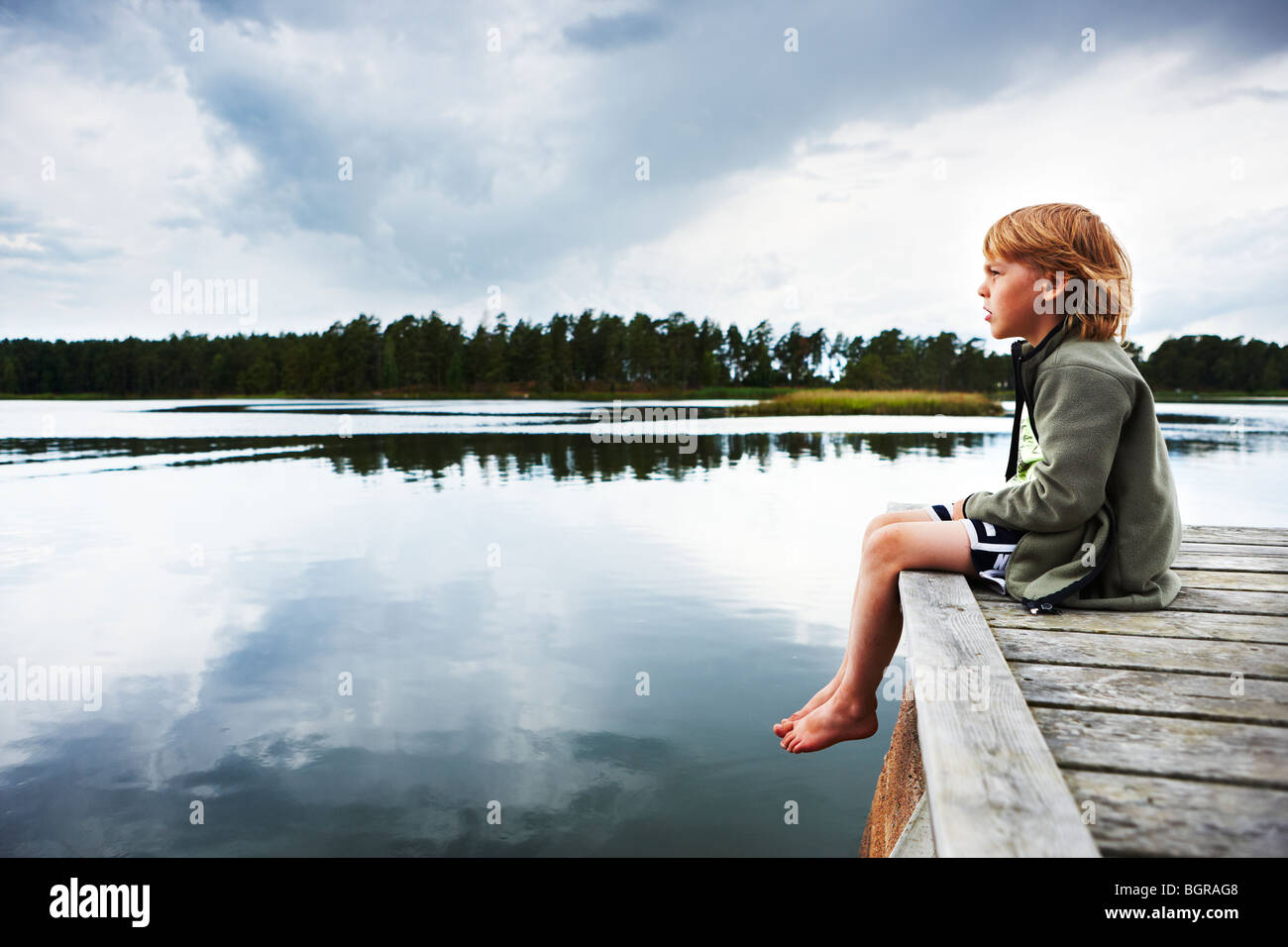 A boy sitting on a jetty, Sweden Stock Photo - Alamy