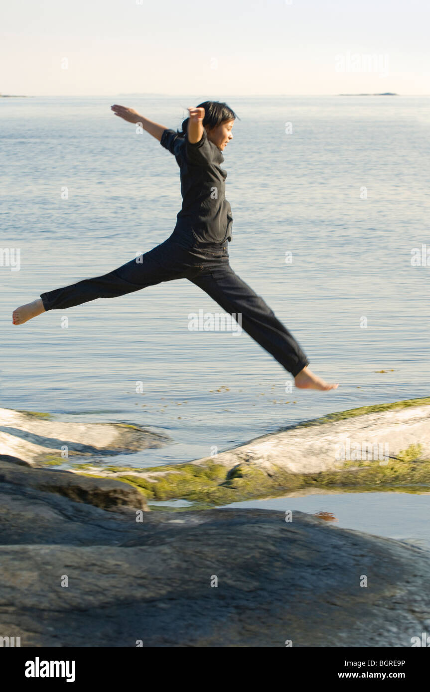 Young woman jumping on rocks by the sea, Sweden Stock Photo - Alamy