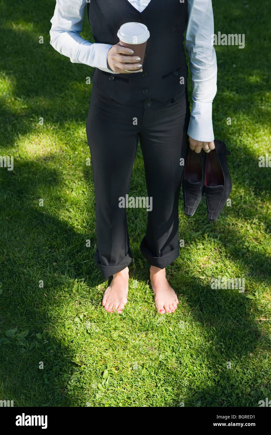A barefooted businesswoman standing on the grass, Stockholm, Sweden ...
