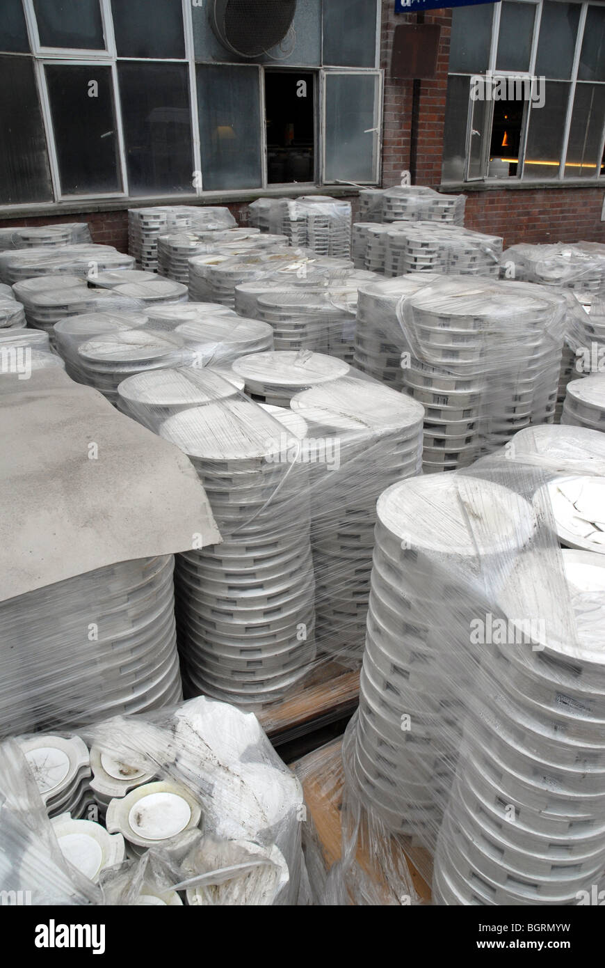 Pallets and stacks of plates and other pottery crockery, outside a ...