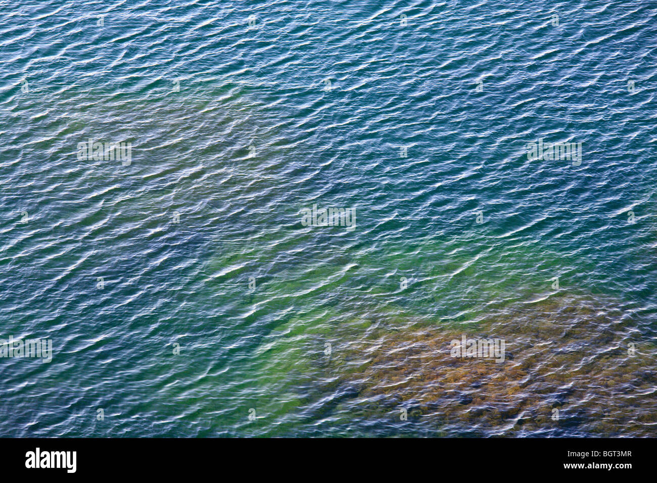 transparent coastal azure water surface with some stones on bottom ...