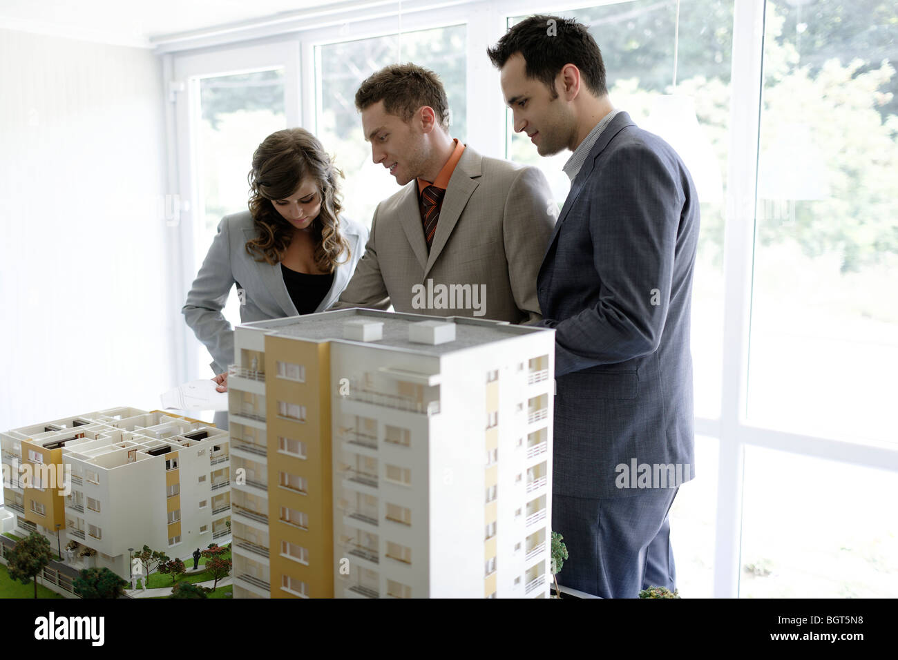 man and woman looking at small architectural building model being ...