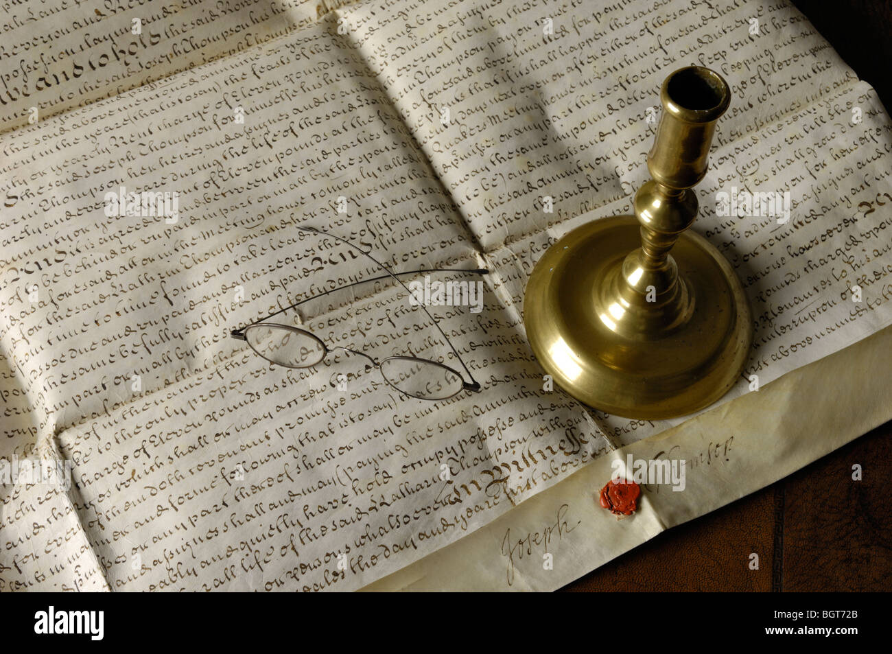 Ancient documents, written in English, spectacles and brass candlestick ...