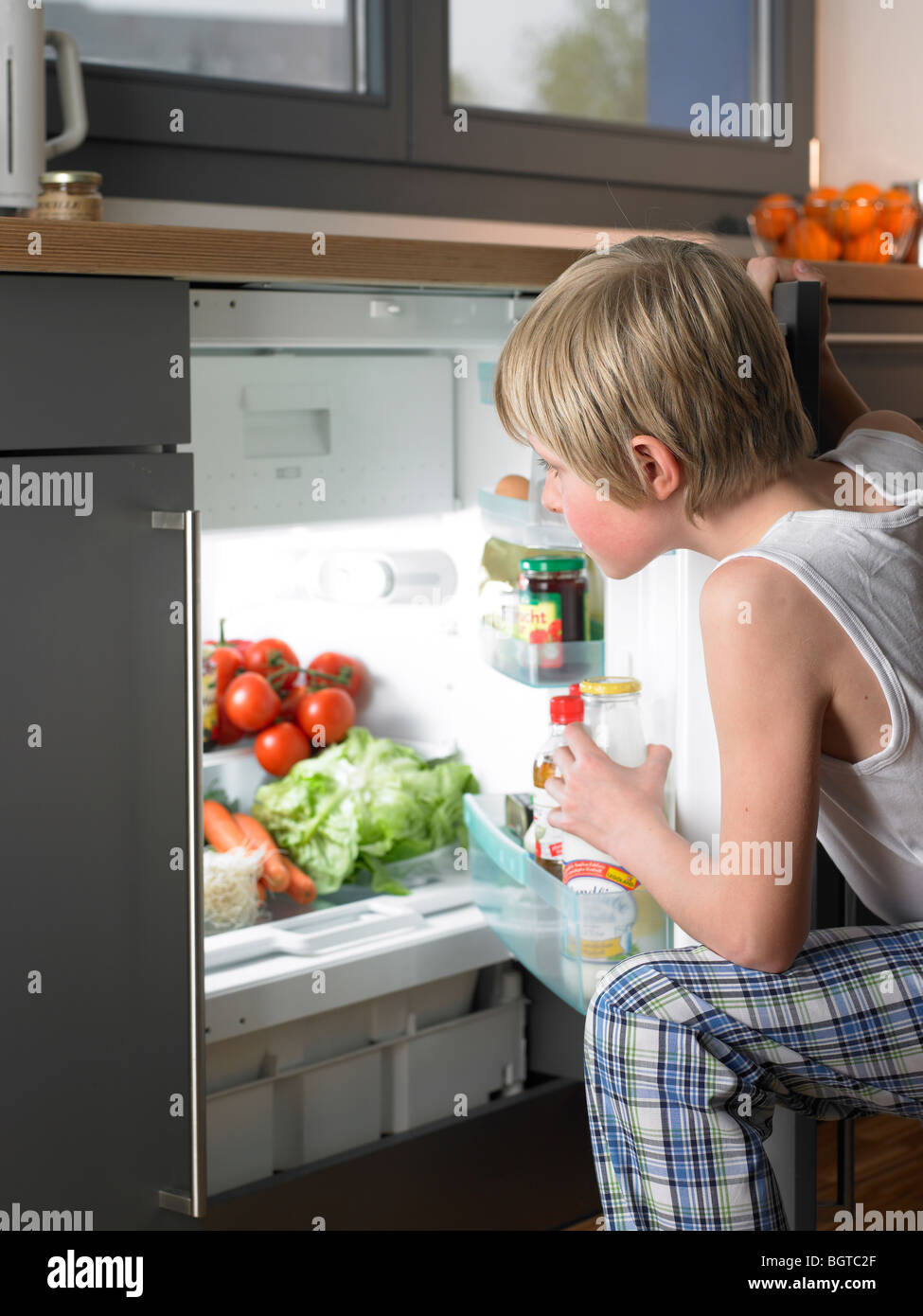 young boy kneeling in front of open fridge Stock Photo - Alamy