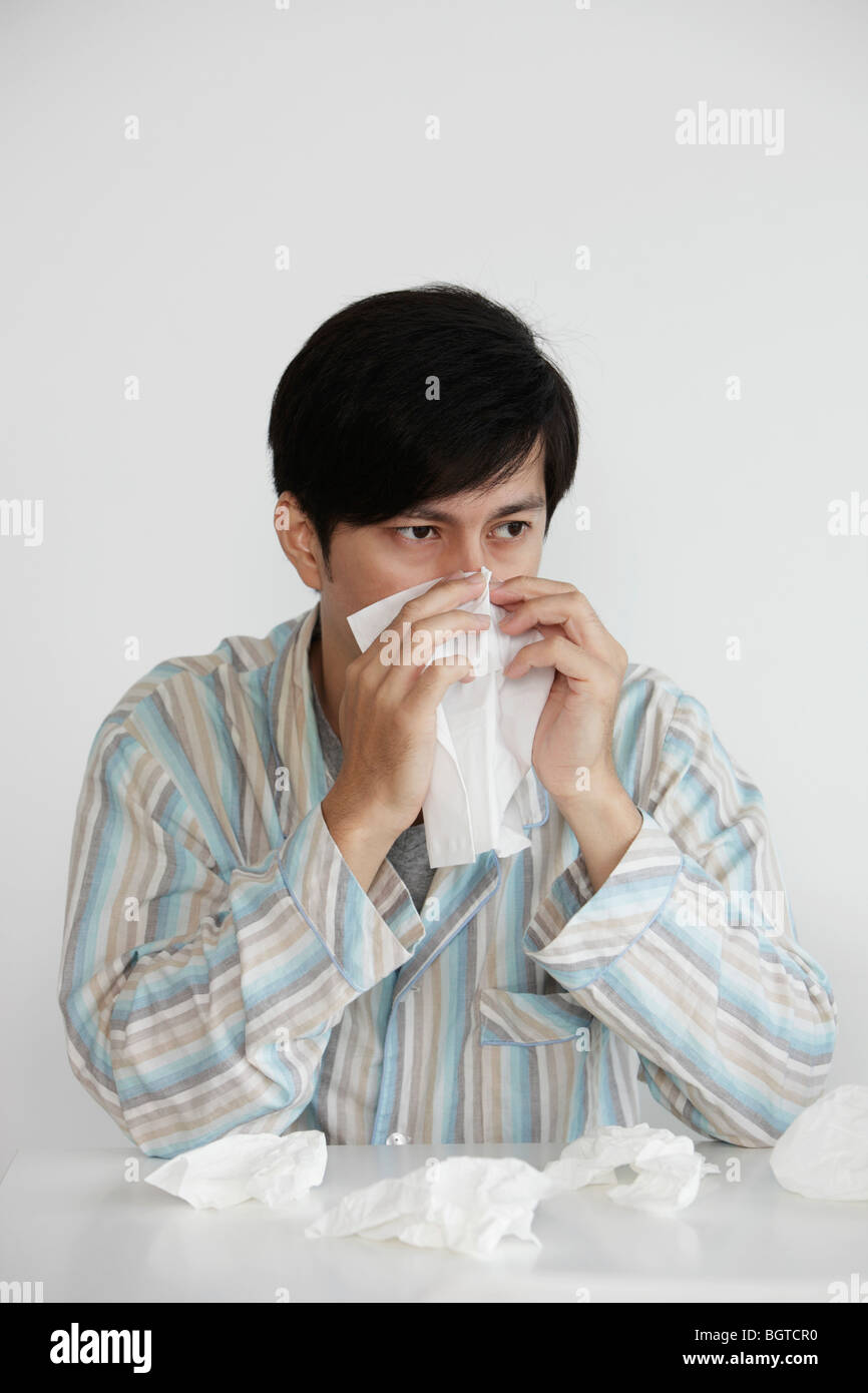 young man blowing his nose with tissue Stock Photo - Alamy