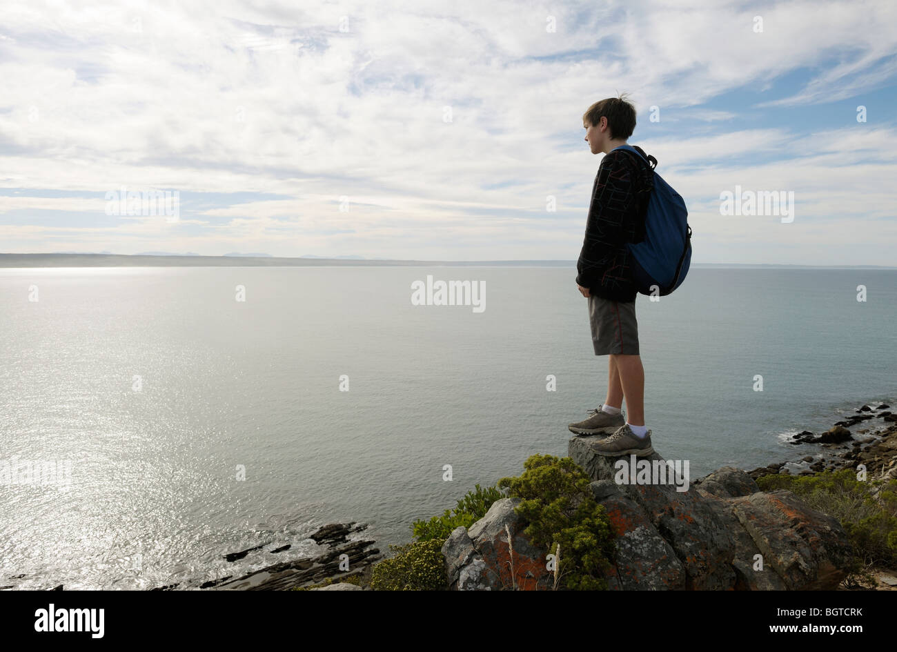 Teenage hiker watching sunrise over sea, Cape Infanta, Western Cape ...