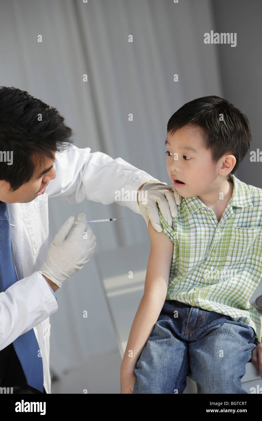Doctor giving young boy an injection Stock Photo - Alamy