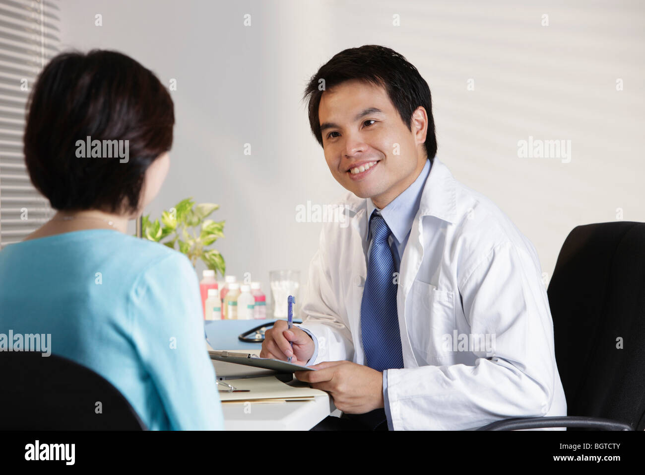 Doctor looking at patient in office Stock Photo - Alamy