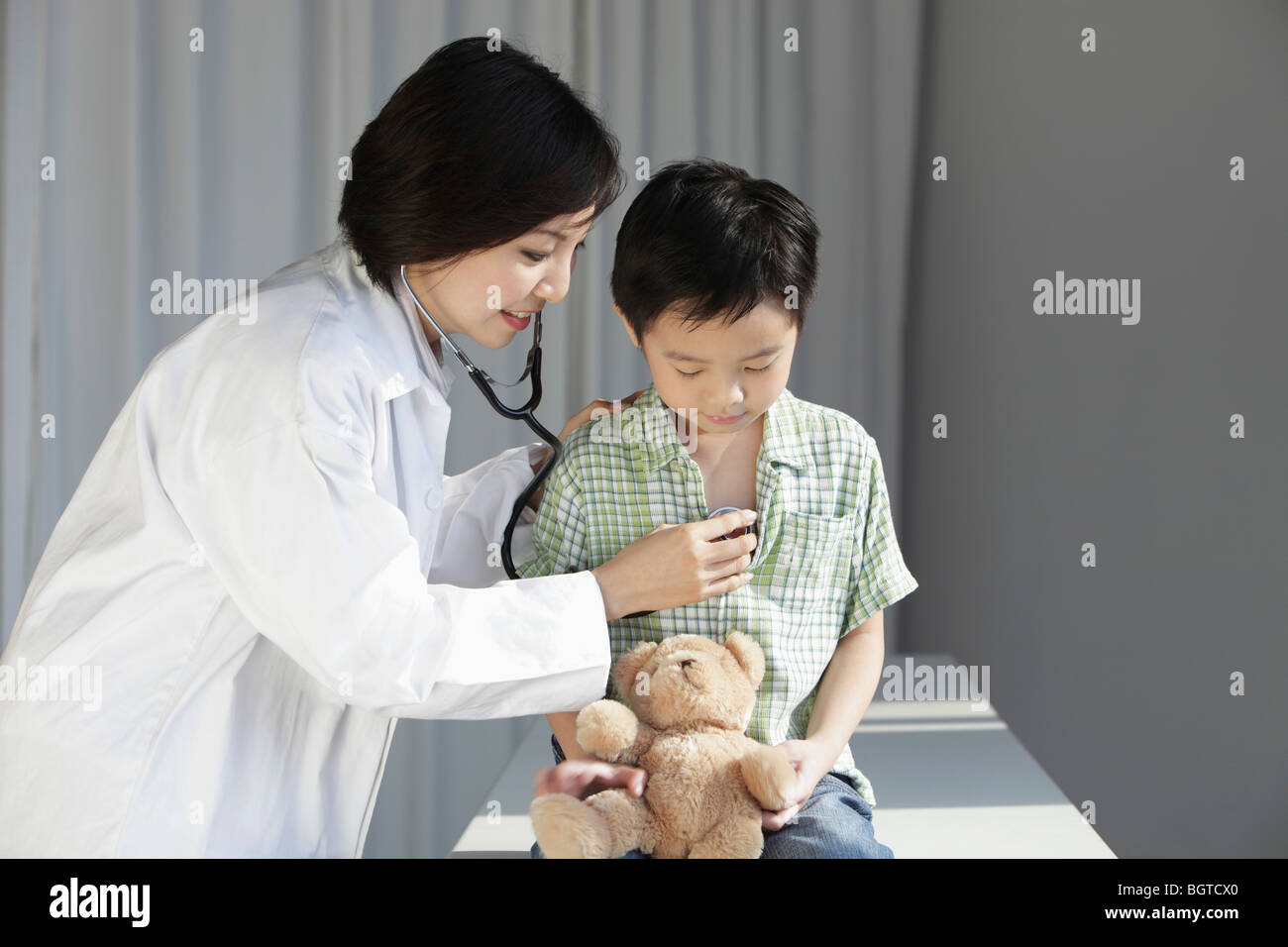 Doctor listening to young boy's heart Stock Photo - Alamy