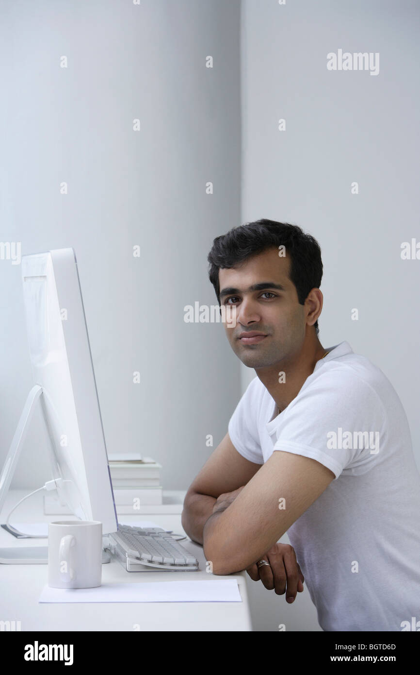 Indian man working on computer, looking at camera Stock Photo - Alamy