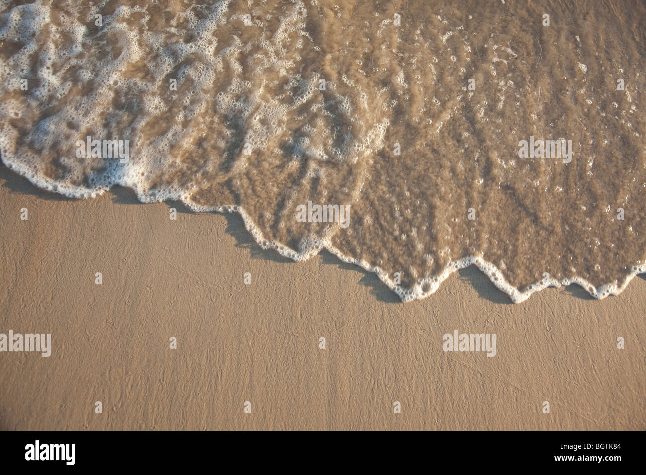 Gentle surf lapping against a golden shore Stock Photo - Alamy