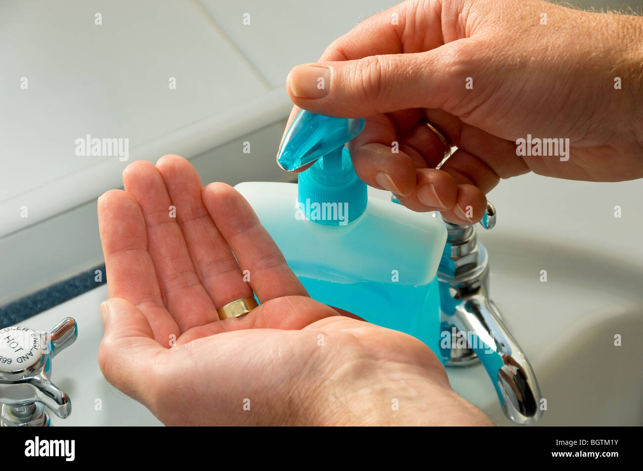 Close up of man using liquid soap to wash his hands in bathroom sink ...