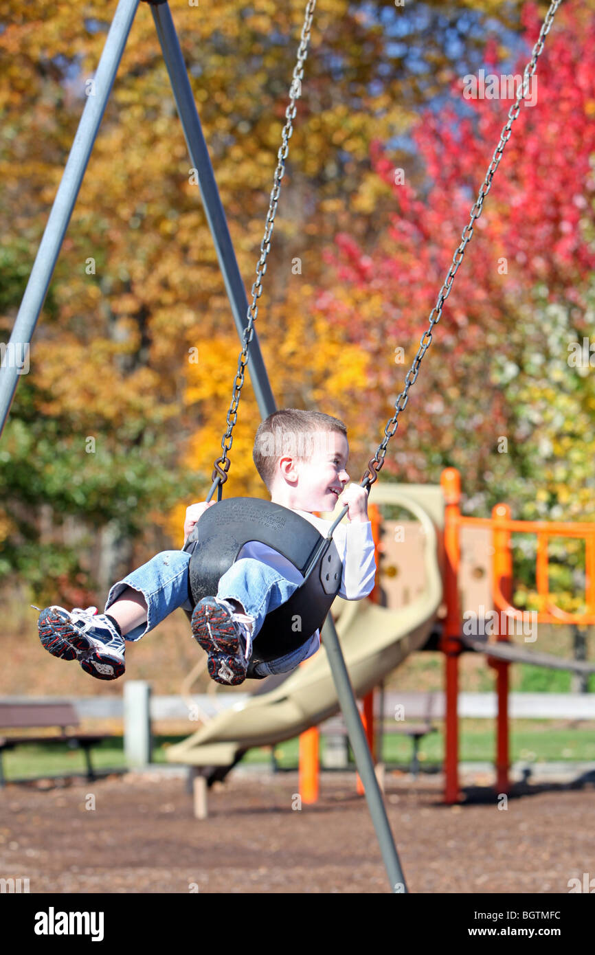 Happy boy on swing during fall Stock Photo - Alamy