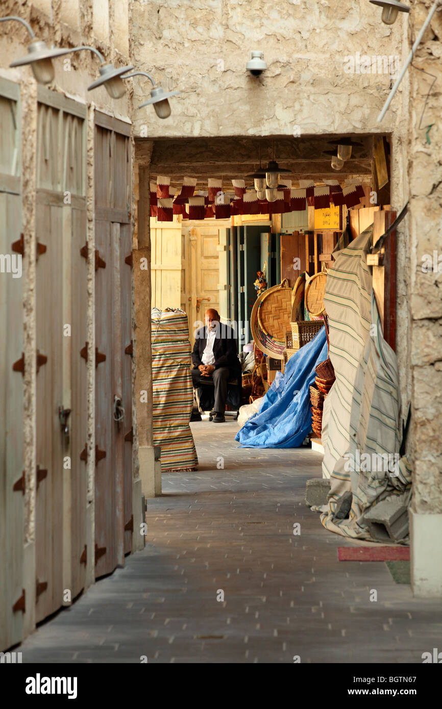 A shopkeeper sitting outside his store on an alley in Souq Waqif, Doha ...
