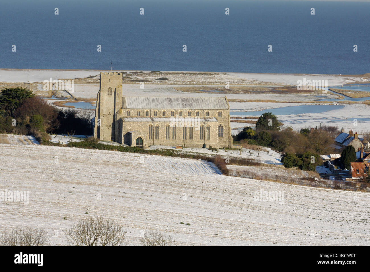 Salthouse village Church, St Nicholas, with snow covered roofs and ...