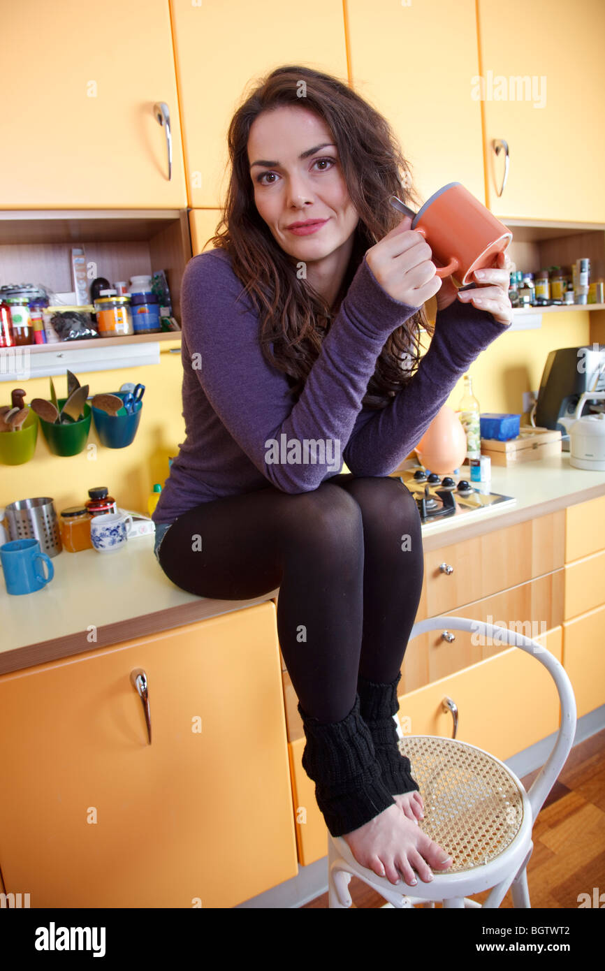 woman sitting in kitchen with mug of tea Stock Photo - Alamy