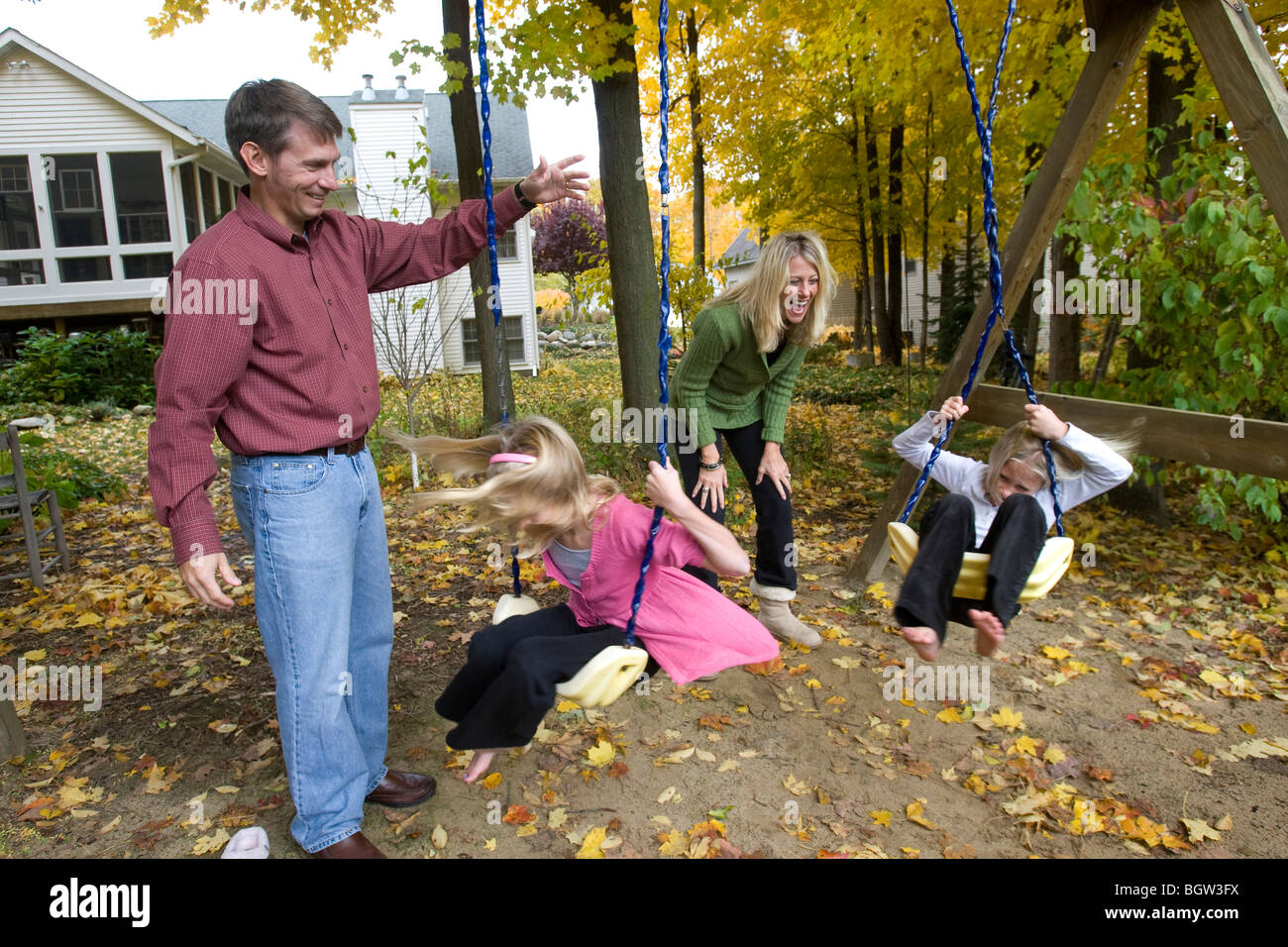 family having fun at swingset in backyard Stock Photo - Alamy