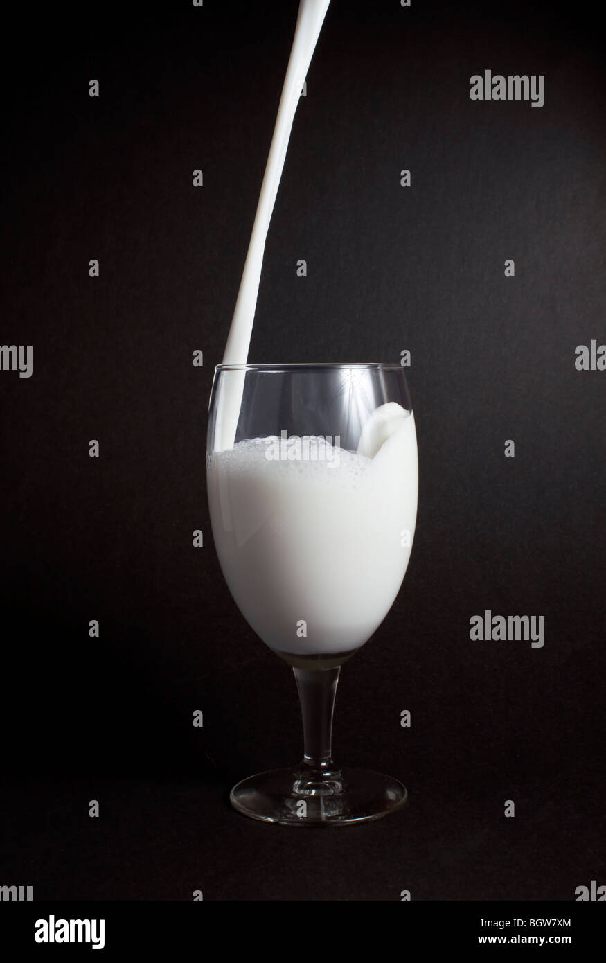 Stream of Milk Falling into a Fancy Wine Glass On Black Background ...