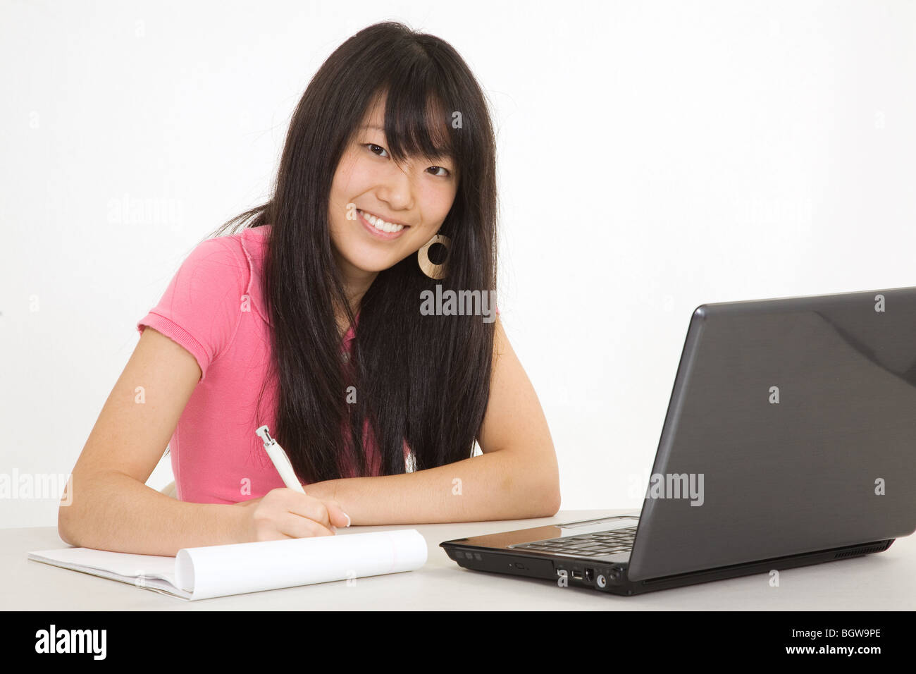 Asian teenager working on a the laptop computer on white background ...