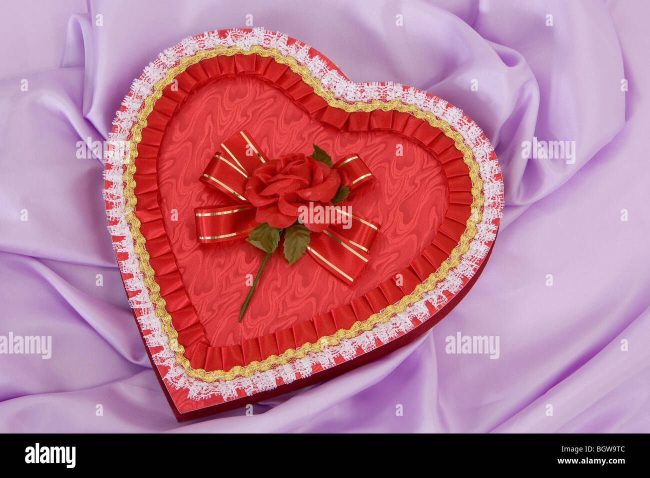 Heart shaped box of candy laying on satin Stock Photo - Alamy