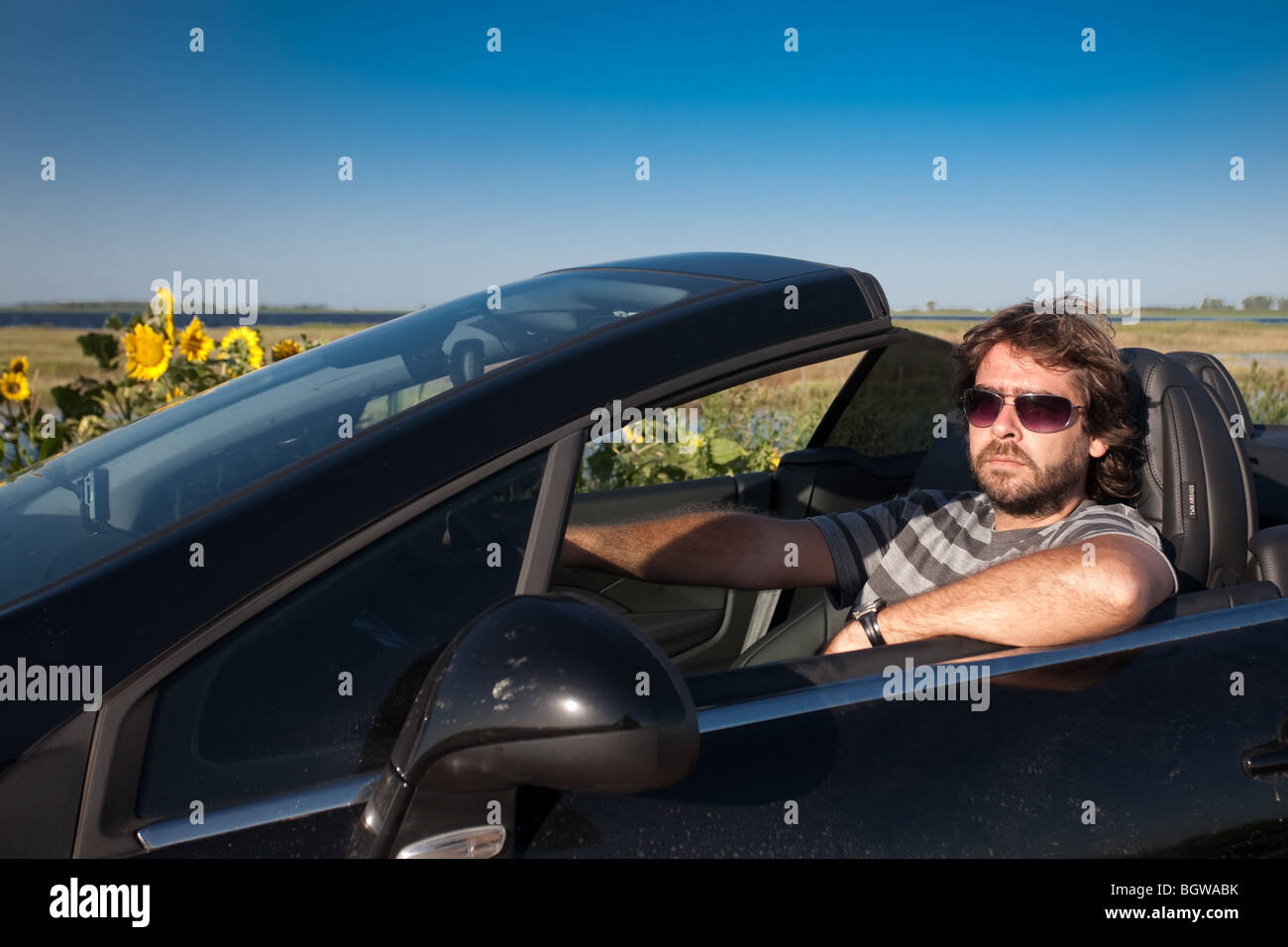 A man driving a convertible car in a road in the countryside Stock ...