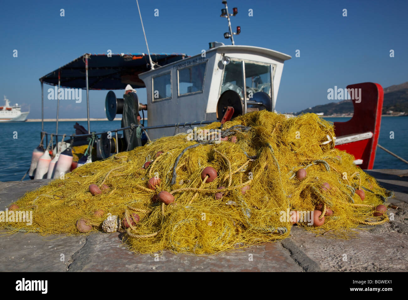 yellow fishing net with fishing boat in background Stock Photo - Alamy