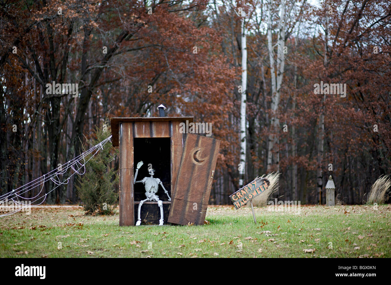 A skeleton waves from an outhouse in a Halloween display setup along a ...