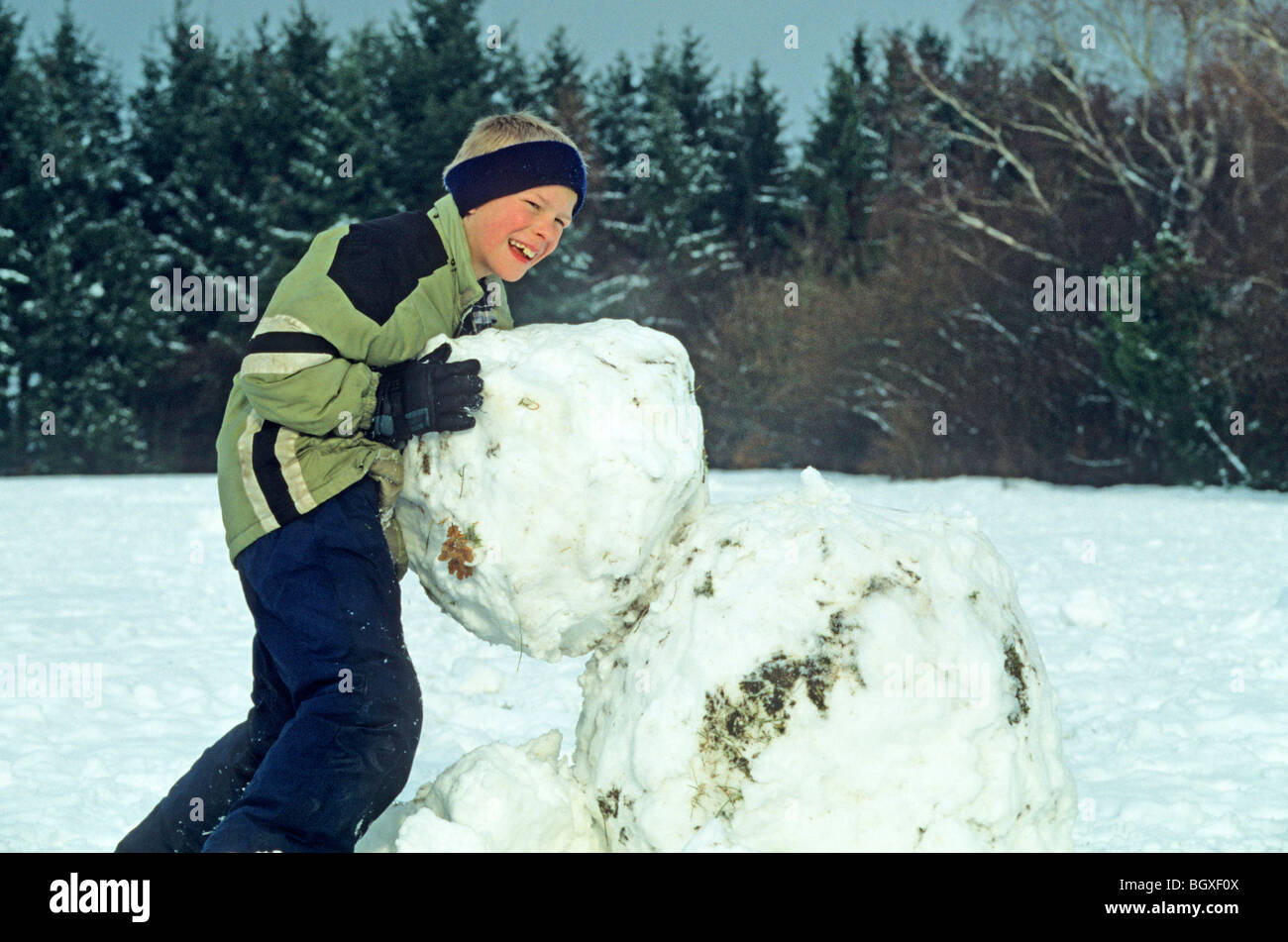 young boy building a snowman Stock Photo - Alamy