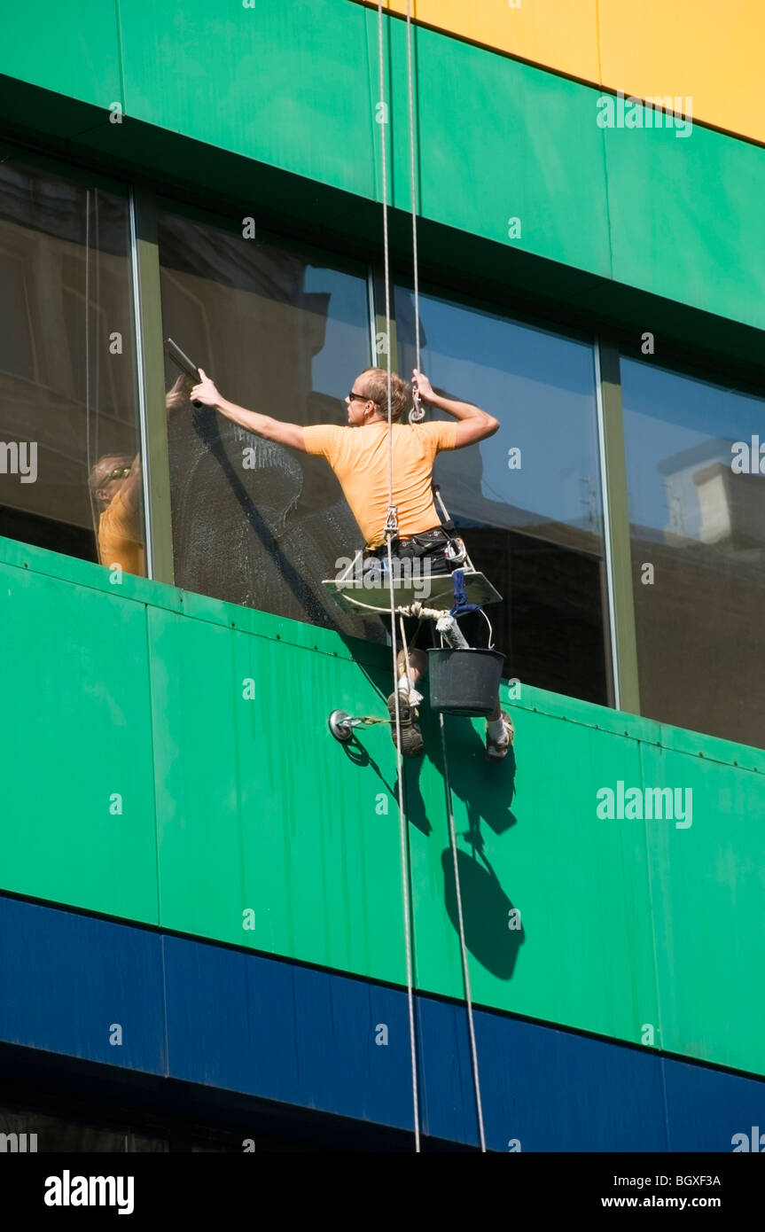 Close-up of one office window cleaner suspended high up in a seat ...