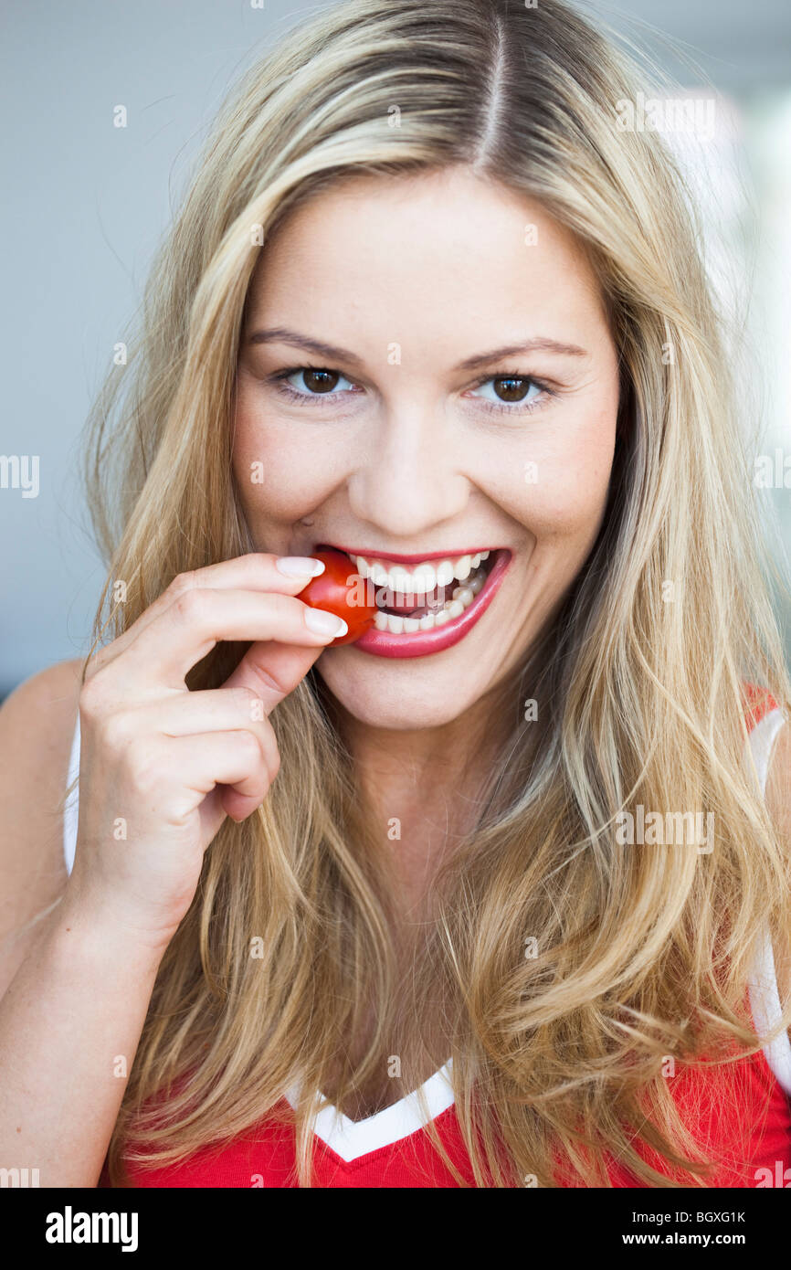 Young woman nibbling on tomato Stock Photo - Alamy