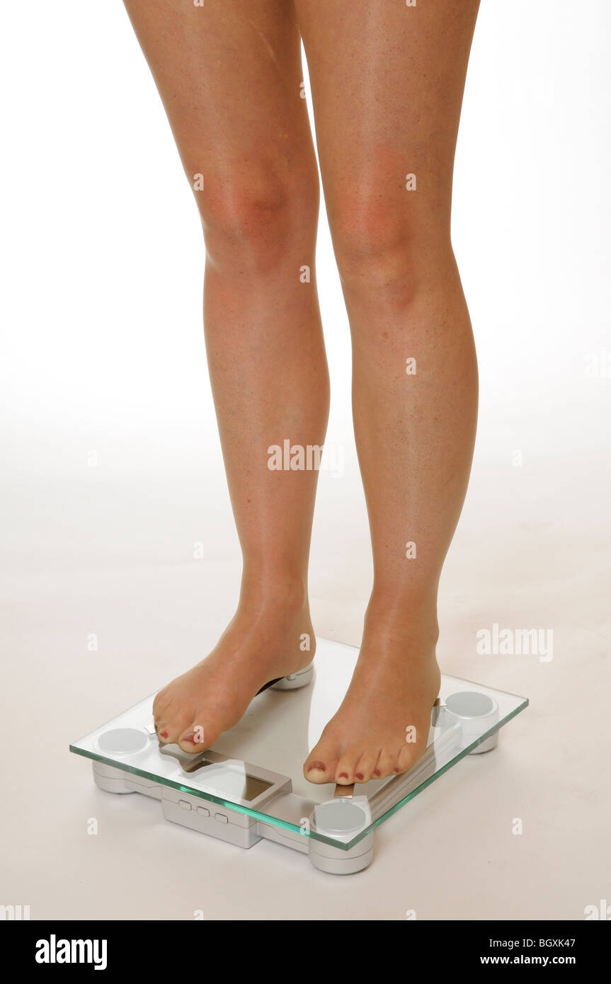 Woman standing on bathroom scales Stock Photo - Alamy