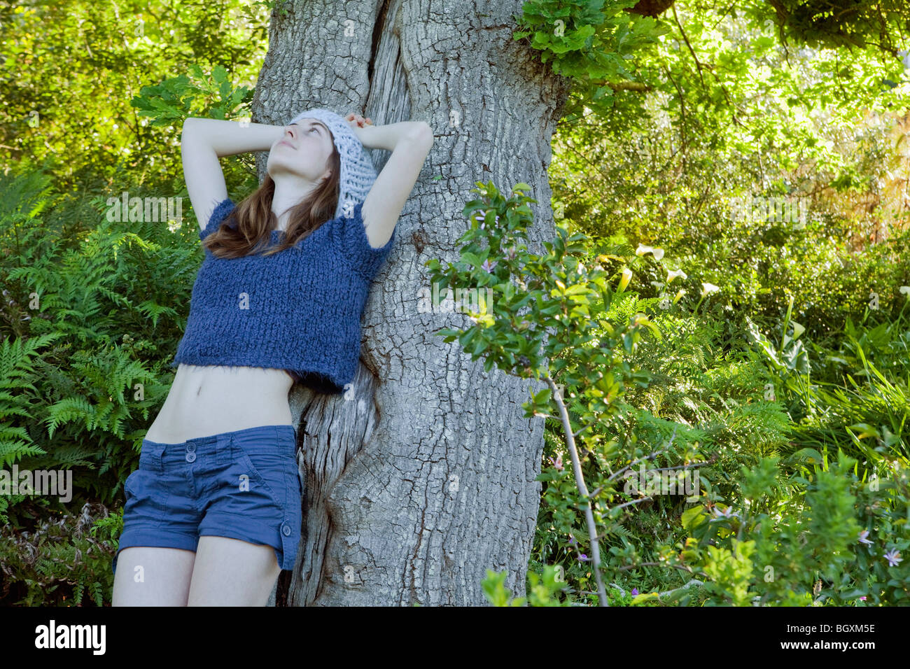 Girl leaning against tree Stock Photo - Alamy