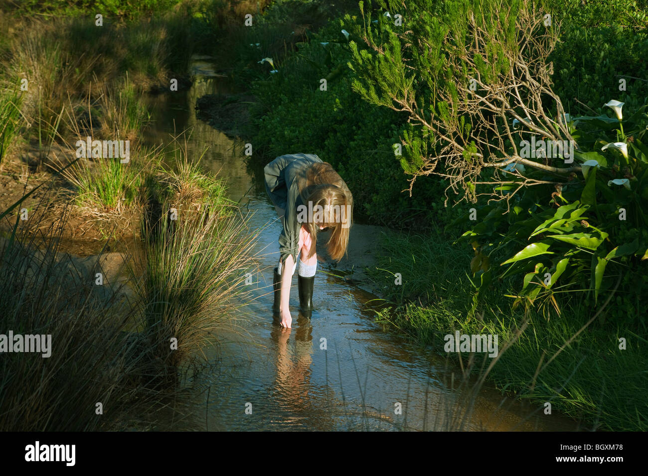 Girl bending down in stream Stock Photo - Alamy